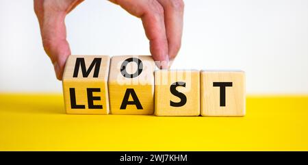 Most or least symbol. Businessman turns beautiful wooden cubes and ...