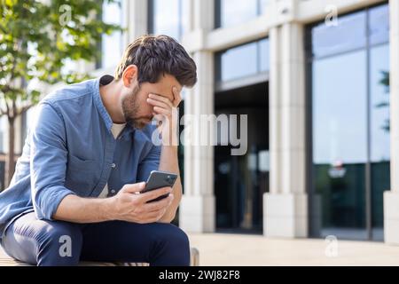 Stressed mature bearded man sitting on a chair with hand on head ...