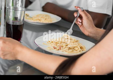 woman's hand holding fork to grab spaghetti and eat it. eating in the ...