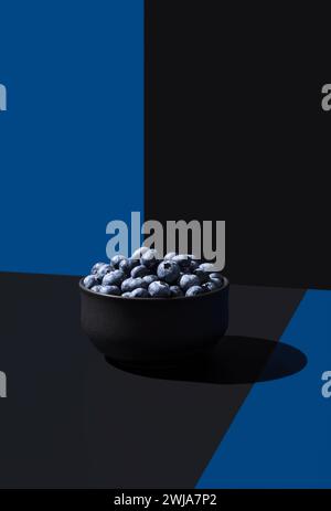 A minimalist composition featuring a black bowl of blueberries on a ...