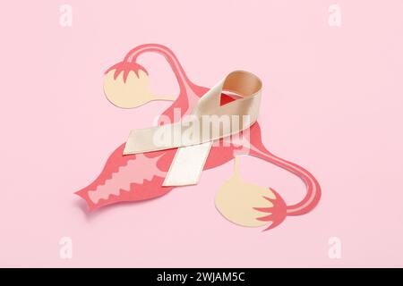 Paper uterus with beige ribbon on light background. Cancer awareness ...