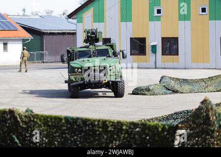 A green armored and camouflaged military vehicle driving at a show ...