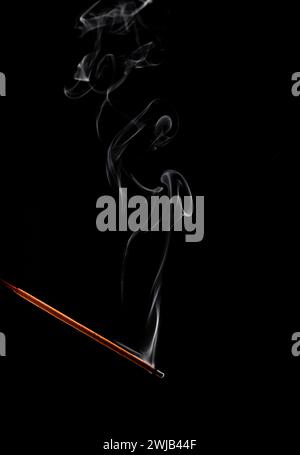 indian incense stick with smoke on black background indoor closeup ...
