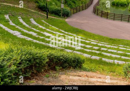Amphitheater seating in public park made of concrete blocks with trees ...