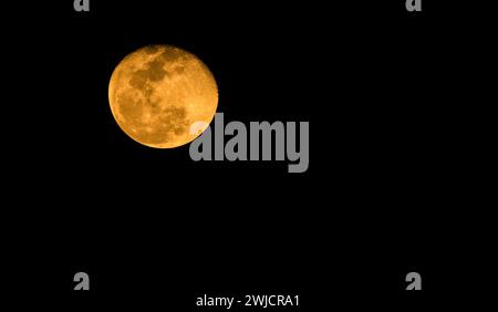 Waning gibbons moon in night sky with yellowish glow taken on February ...