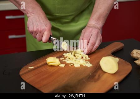Man chef chopping ginger finely on a wooden board with a very sharp ...