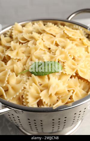 Pasta in a metal colander on a dark wood table with moody lighting ...