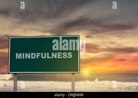 Road sign with mindfulness text and ocean view with sunset scene ...