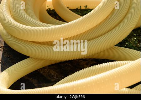 Perforated yellow drainage pipe with slots in a roll twisted in a ...