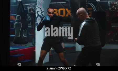 Confident African American fighter hits punching bag while training in ...