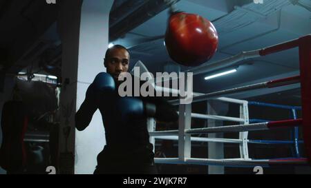 Confident African American fighter hits punching bag while training in ...