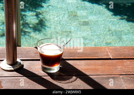 Morning coffee at poolside. Coffee glass standing near swimming pool ...