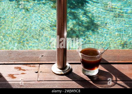 Morning coffee at poolside. Coffee glass standing near swimming pool ...