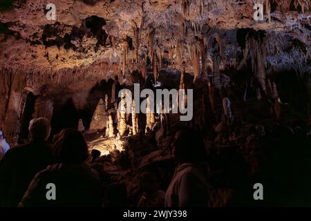 Tourists walking past limestone rock formations in a cave at Florida ...