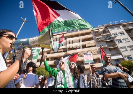 A protester speaks on a megaphone while others march holding flags and ...