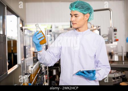 Quality control officer inspects beverage bottling factory line with ...