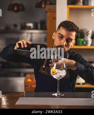 Cocktail making. Using jigger. Barman hand pouring yellow liquid for chilled alcoholic drink ...