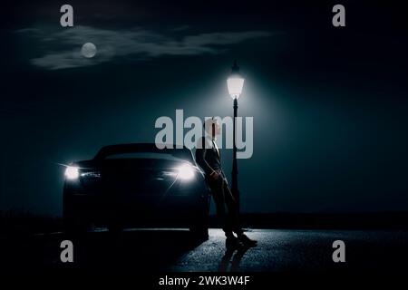 Man leaning against car with lamp post at night, USA Stock Photo - Alamy