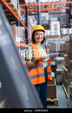 Scanning woman in hard hat and vest, operating handheld barcode scanner ...