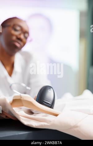 Cash register employee scanning clothes to help customer complete ...