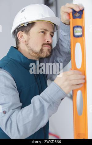 handyman measuring angle of wall with level Stock Photo - Alamy