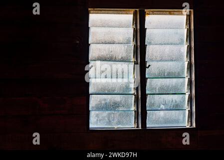 Light hitting closed frosted louvered glass windows against a jet black ...