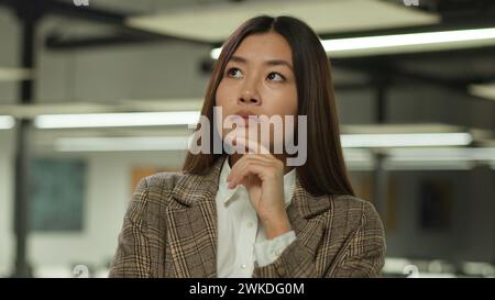 Concentrated pensive Asian girl student looks away thinking about ...