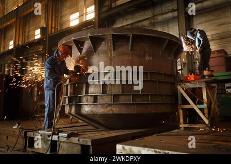 Large workshop with metallurgical plant workers working with cast iron ...