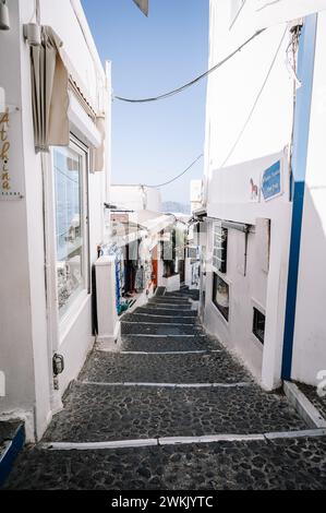 Narrow residential alley with white walls, flowers, and traditional ...