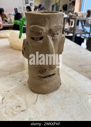 Pottery artist placing clay objects on shelves to dry before firing ...