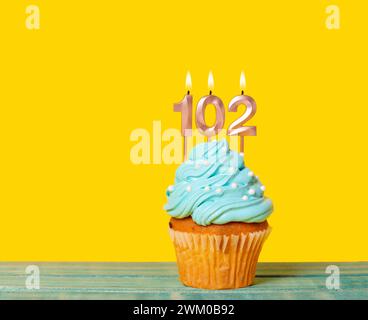 Birthday cake with number 102 candle - Sparkling orange background with ...