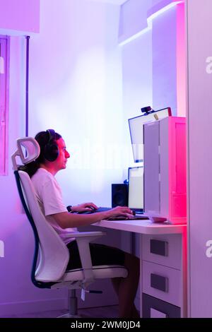 Professional gamer wearing headphones and playing game on computer ...