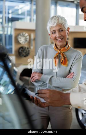 Salesperson discussing with smiling customer in car showroom Stock ...