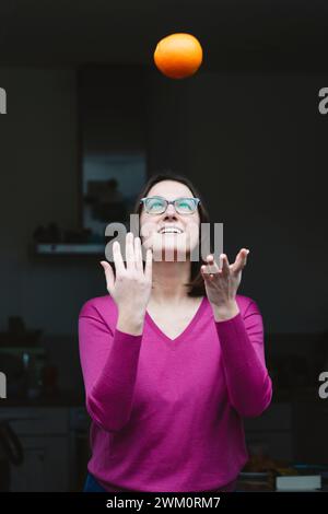 Smiling woman juggling oranges standing by tree Stock Photo - Alamy