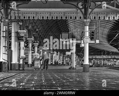A railway station platform, lined by columns, curves, into a main concourse. A historic 19th ...