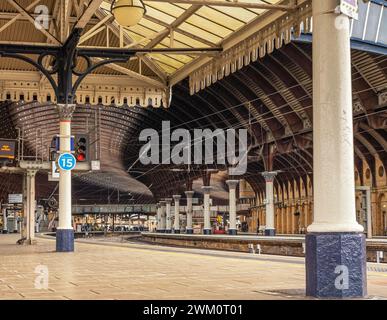 A railway station platform, lined by columns, curves, into a main concourse. A historic 19th ...