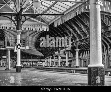 A railway station platform, lined by columns, curves, into a main concourse. A historic 19th ...