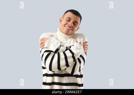 Young man hugging himself on beige background, back view Stock Photo ...