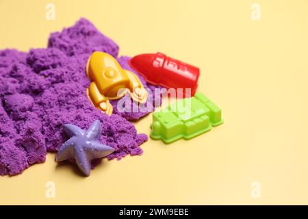 Violet kinetic sand and plastic toys on beige background Stock Photo ...
