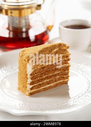 Russian honey cake slice on white plate on off white textile tablecloth ...