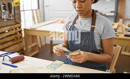 African woman counting south african rands in a carpentry workshop ...