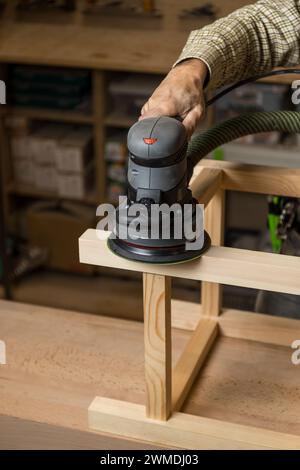 Close up of sanding a wood with orbital sander at workshop electric ...