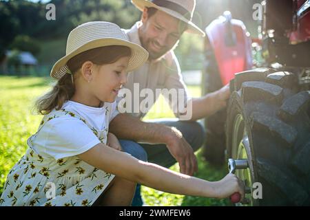 Farmer father riding tractor with his daughter. Girl growing up on ...