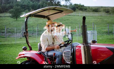 Farmer father riding tractor with his daughter. Girl growing up on ...
