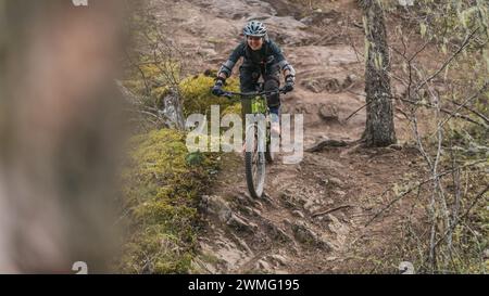 Woman mountain biking coming down a big rock Stock Photo - Alamy
