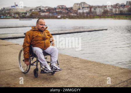 Portrait of happy paraplegic handicapped man in wheelchair in park. He ...