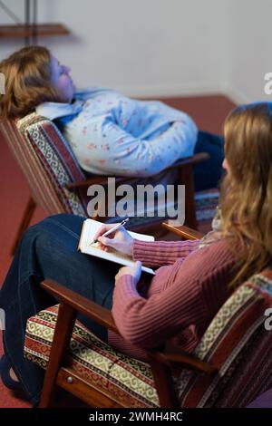 An adult female psychologist interviews a female patient and takes ...