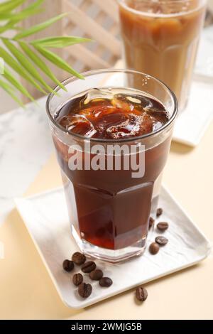 Glass of an iced latte on a beige background with creative shadows ...