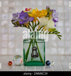 Beautiful flowers. Freesias in multi-colored vases on a white wooden ...
