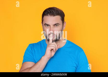 Guy having secret and holding finger on lips. Male model, asks to be ...